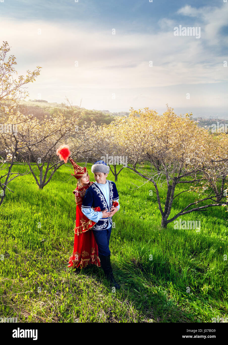 Couple in Kazakh ethnic costume in Spring Blooming apple garden of ...