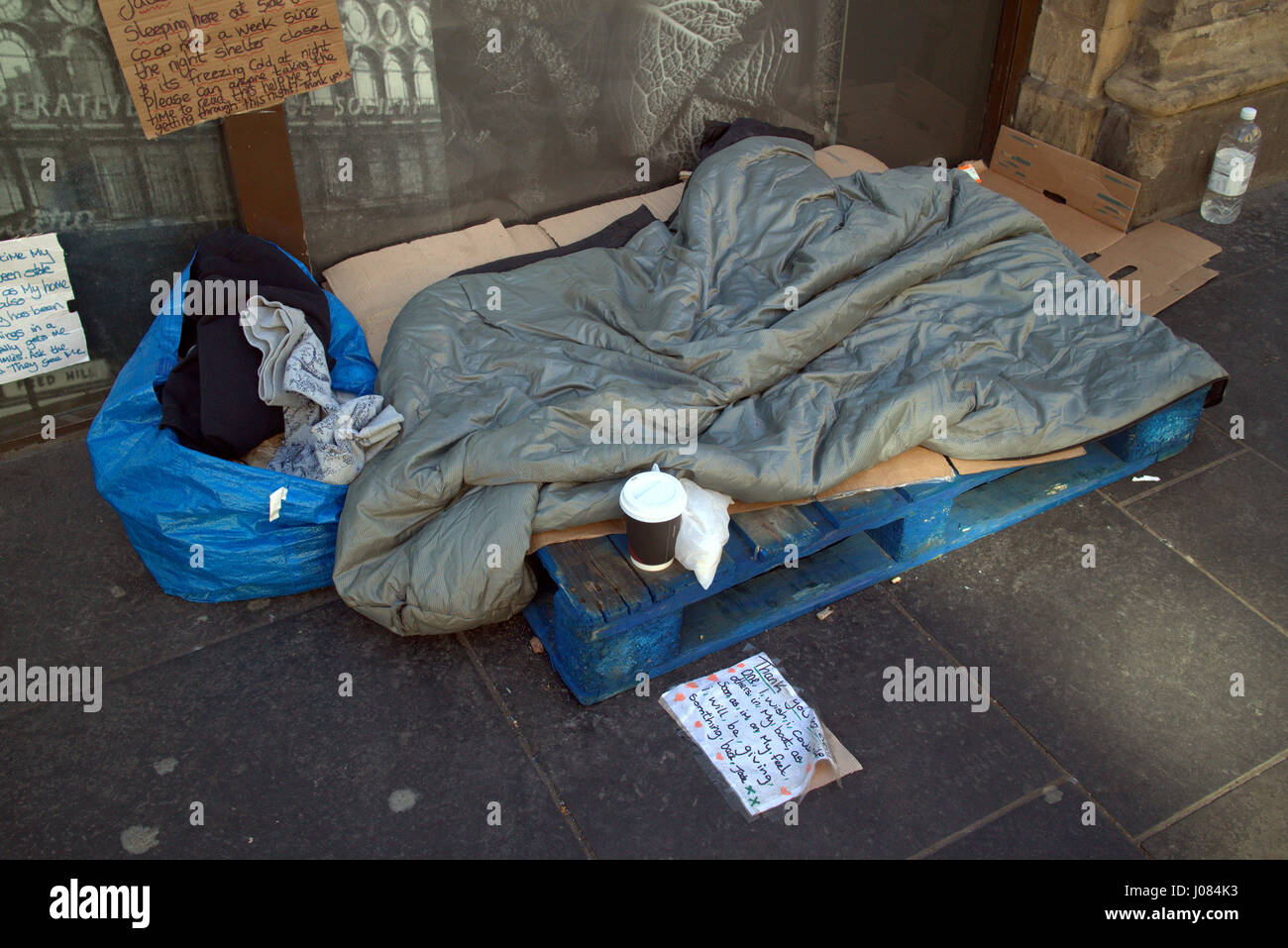 homeless persons street bed with multiple adverts for their plight ...