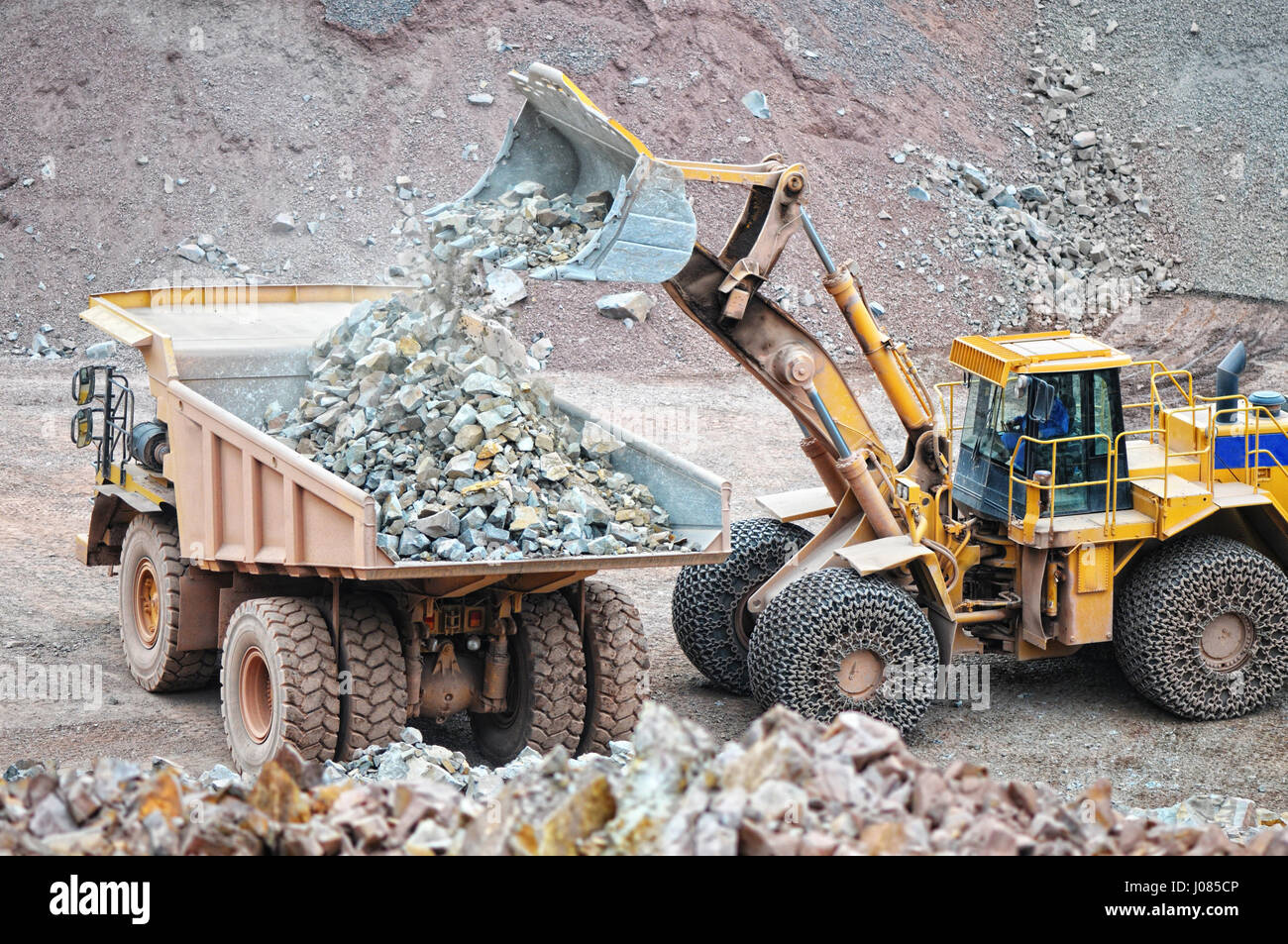 earth mover loading dumper truck with rocks in quarry Stock Photo - Alamy