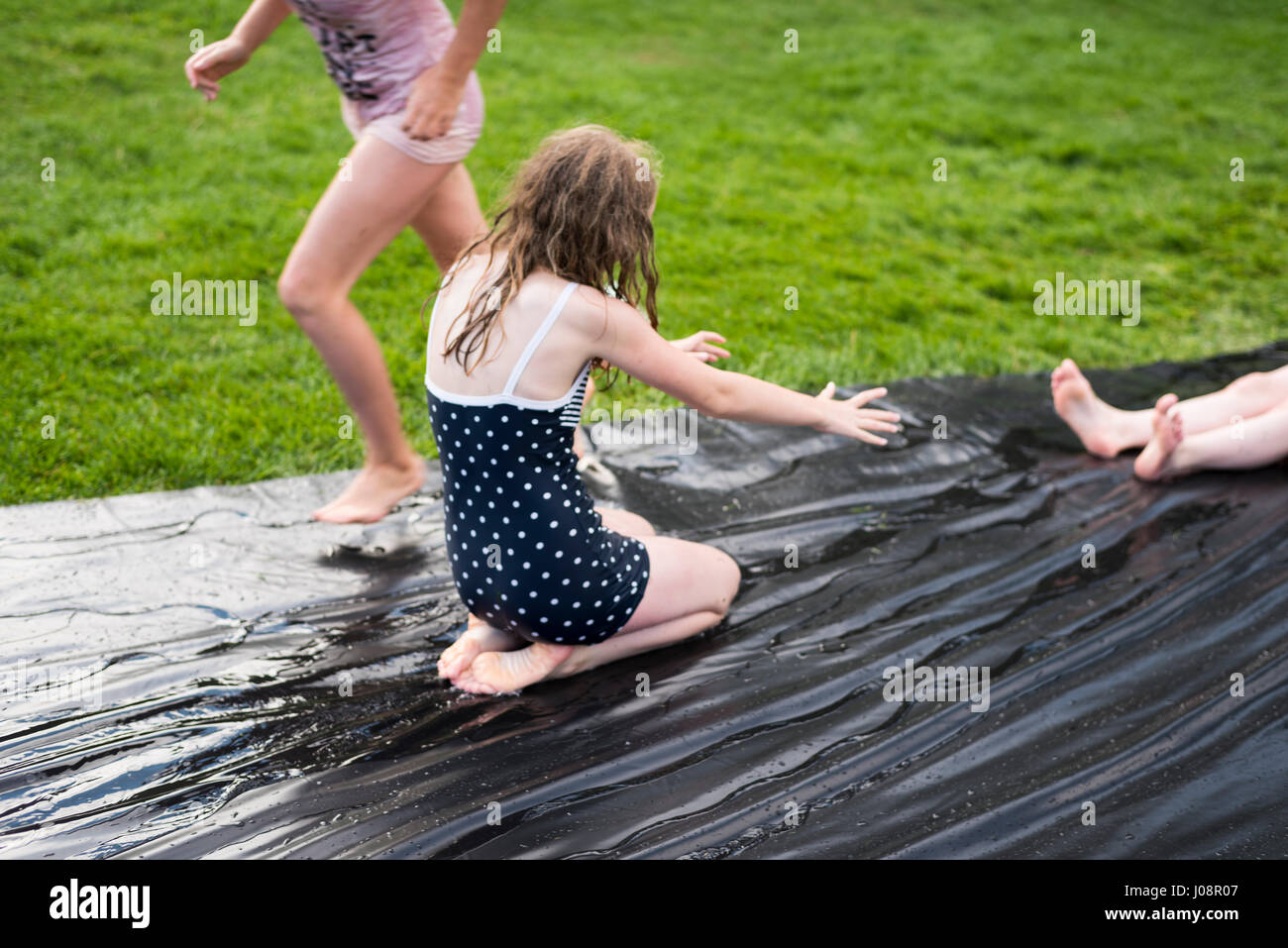Children playing on a water slide at a summer festival Stock Photo - Alamy