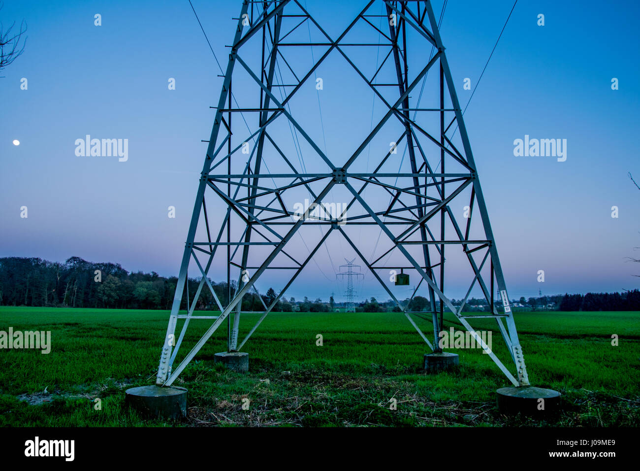 big electric power tower at sunset with a yellow moon in the background ...