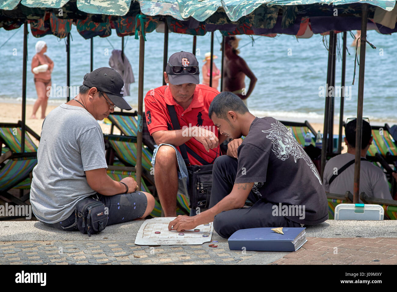 Thailand men playing draughts or checkers using a paper board and ...