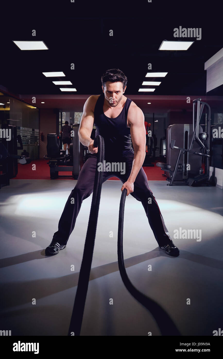 Man is doing exercises working out with a rope in the gym Stock Photo ...