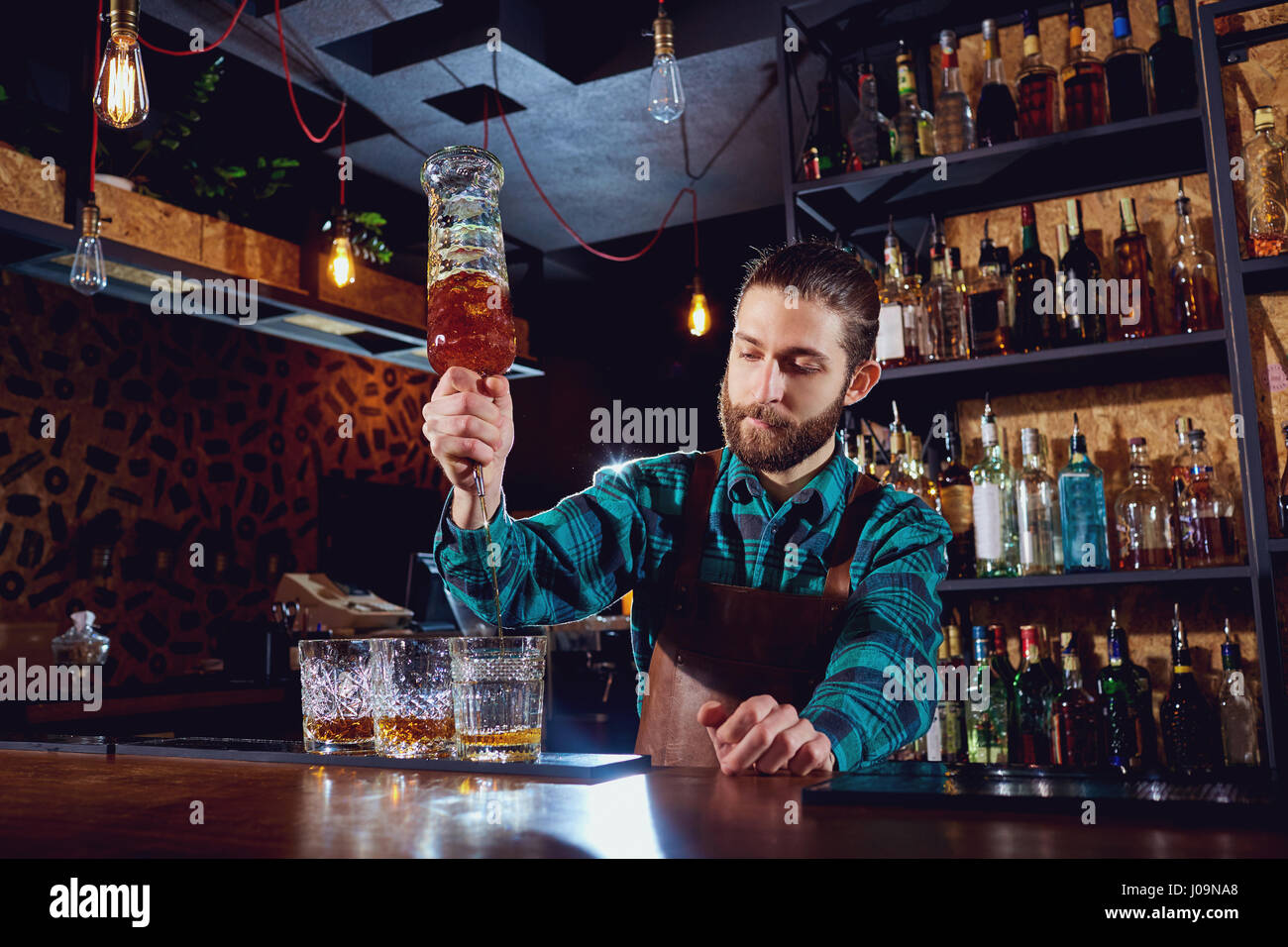 The barman pours alcohol into a glass Stock Photo - Alamy