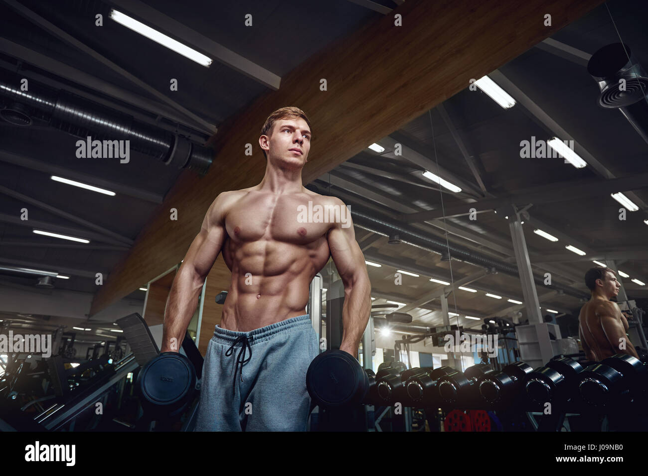Athlete man with dumbbells in hands on a simulator in the gym Stock ...