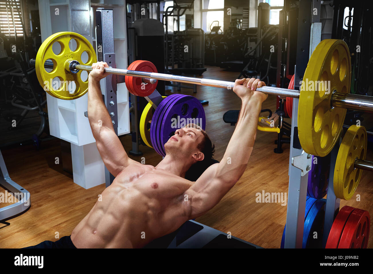 Athlete male doing exercises with a bar lying down in the gym Stock ...