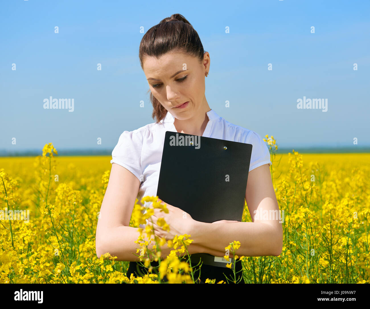 Sad business woman in flower field outdoor with clipboard. Young girl ...