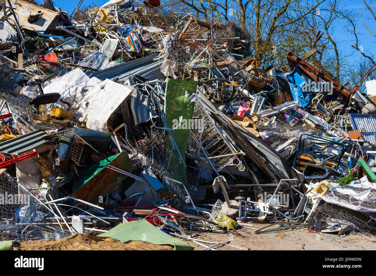 Large pile of metal waste material destined for recycling. Bare trees ...