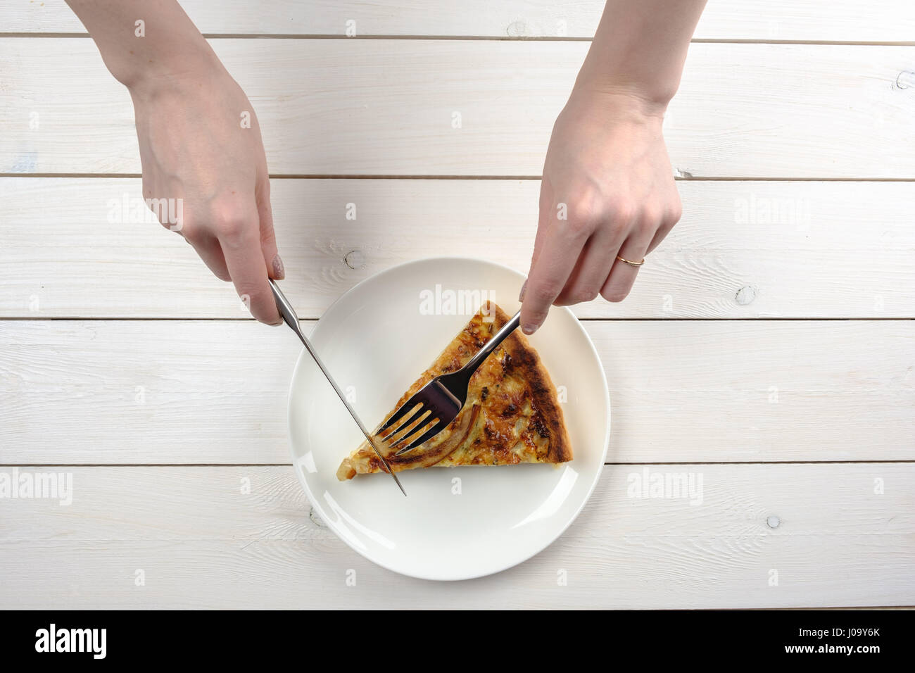 Female hands cutting a tasty piece of pie on a white plate. Top view ...
