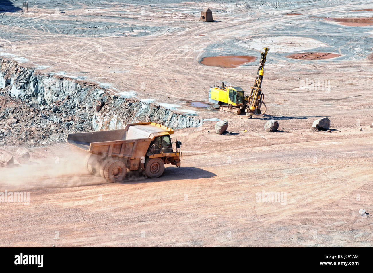 dumper truck driving around in open pit mine of porphyry rock. driller ...