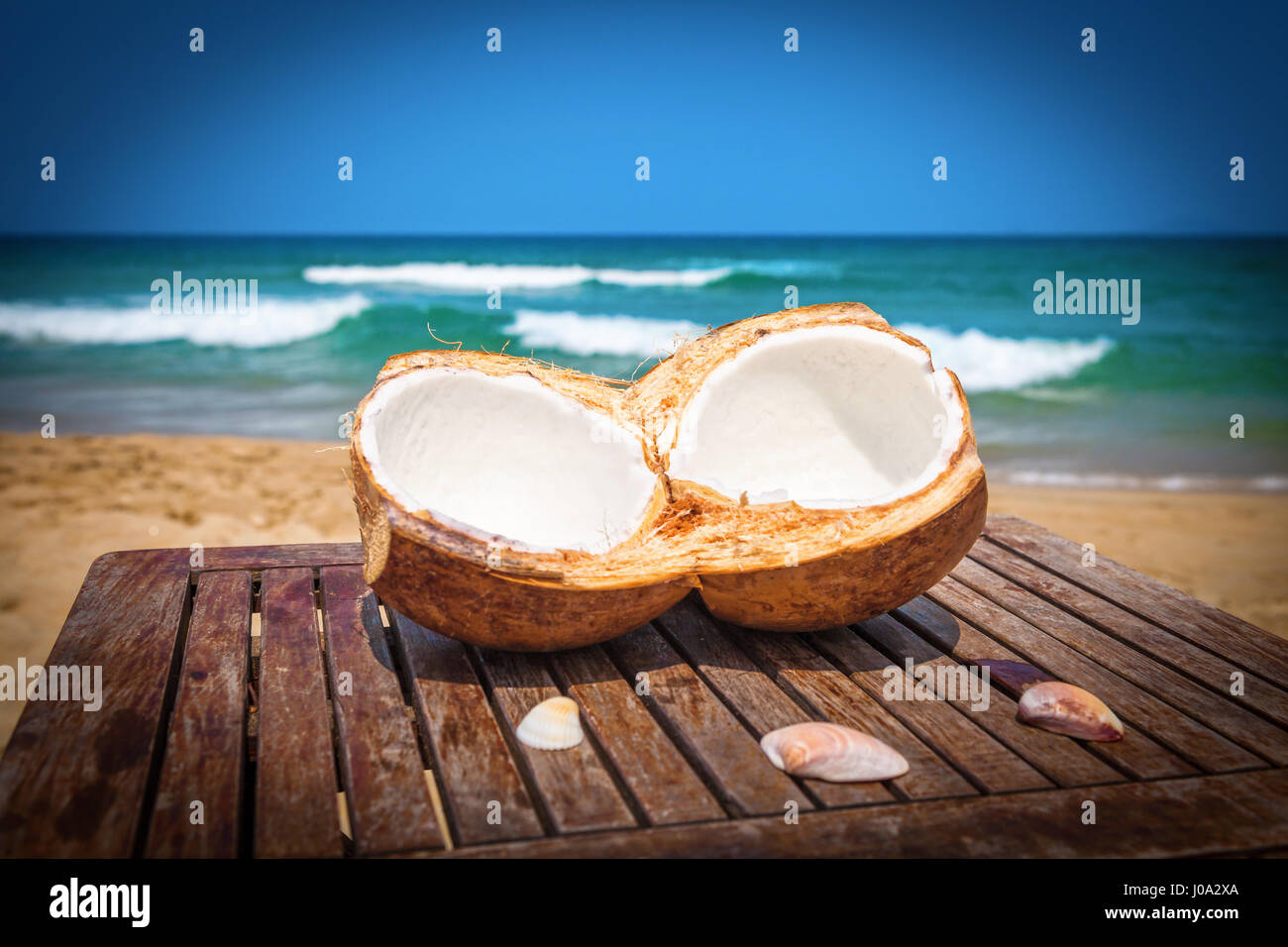 Coconut on the table against beautiful beach and emerald sea Stock ...