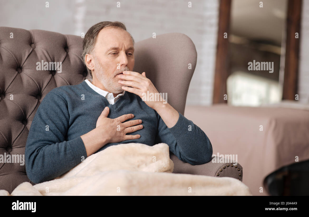 Terrible bronchitis. Senior handsome man is coughing really strongly ...