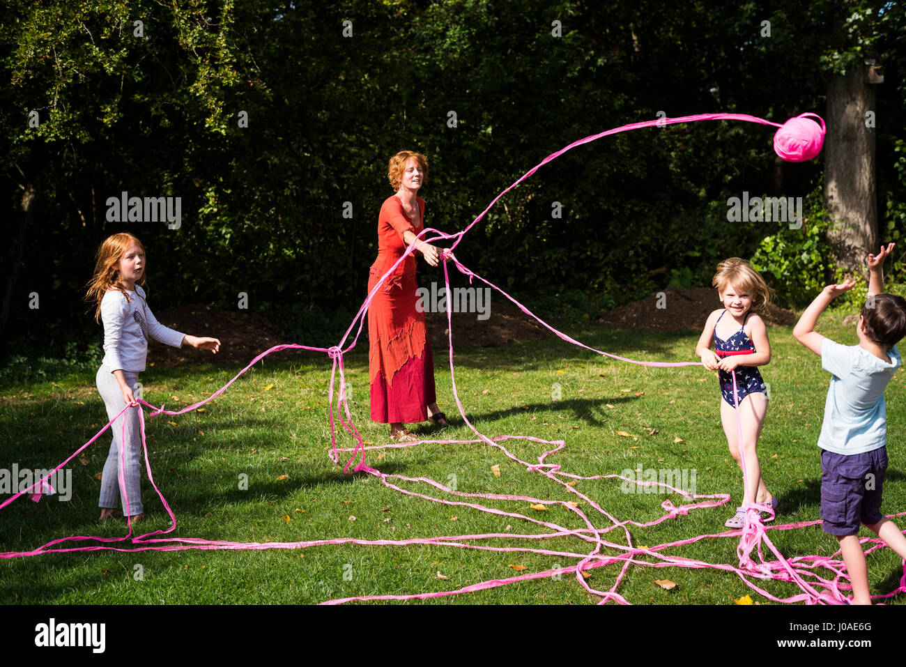 Woman throwing a pink ball of string to children during a drama ...