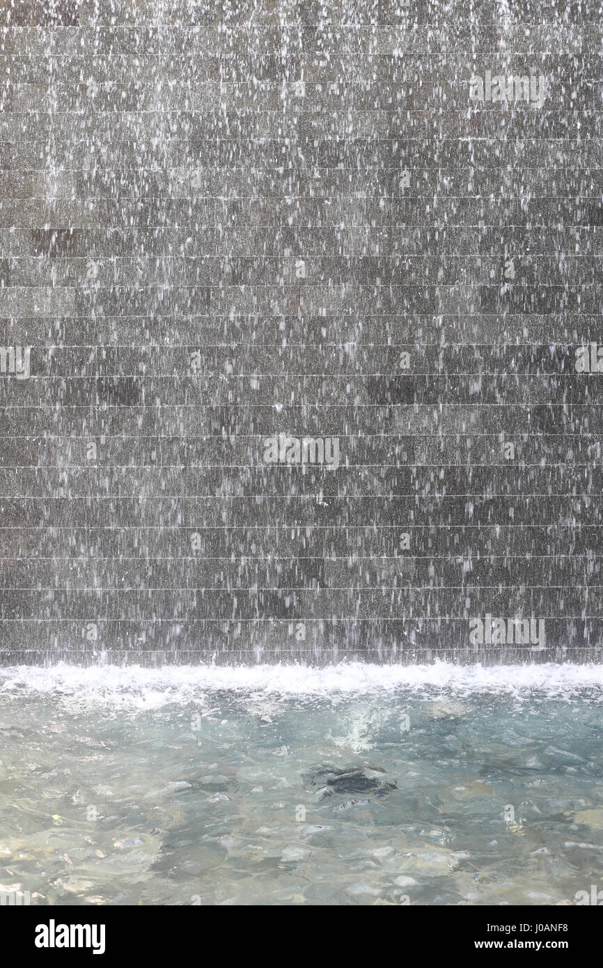 stone wall with water flowing down in pond for design nature background ...