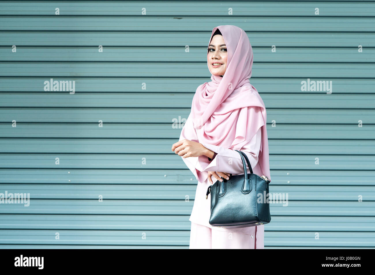 Muslim female holding a handbag with authentic smile Stock Photo - Alamy