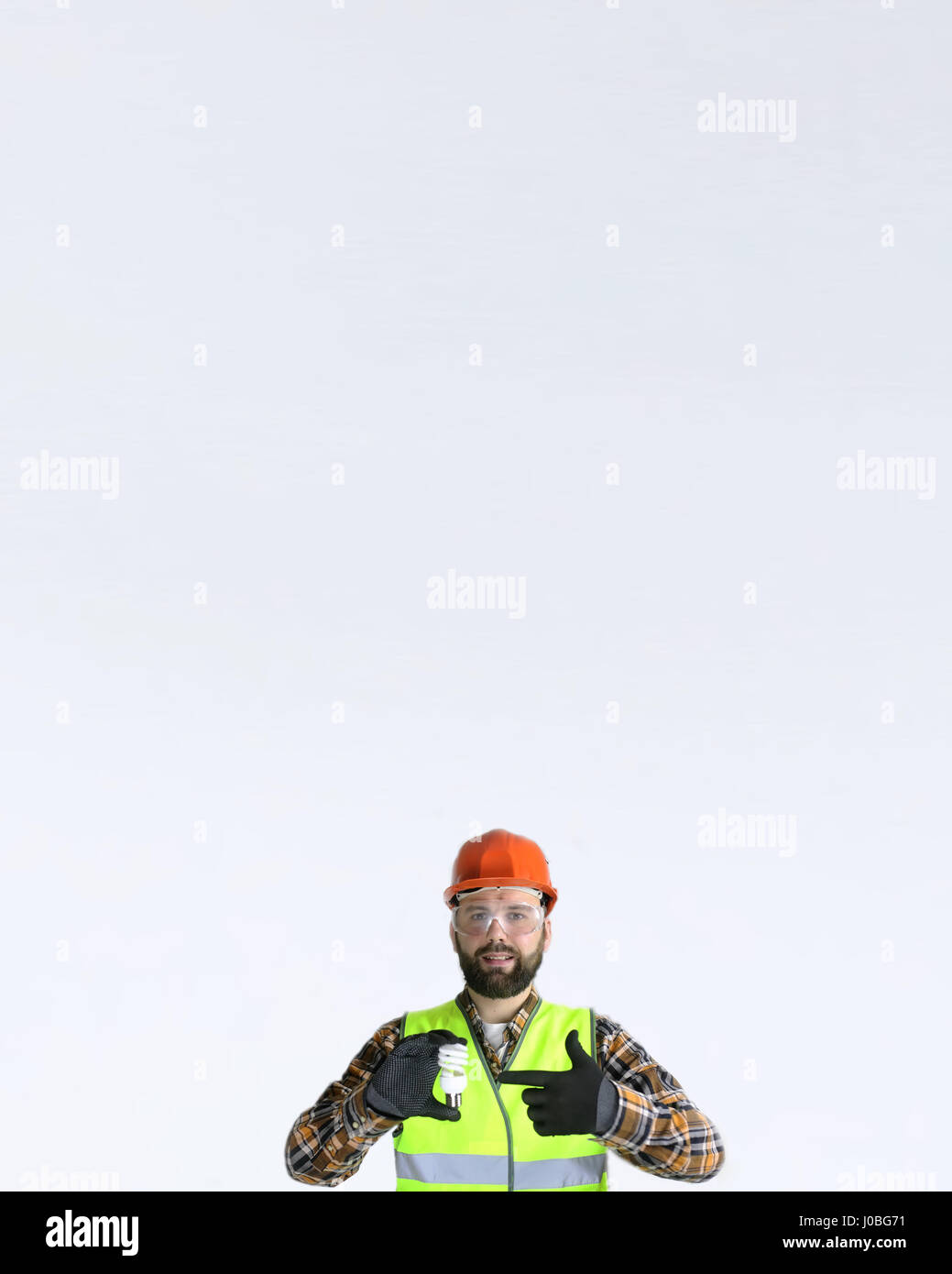 Worker in a helmet and protective clothing with a light bulb in Stock ...