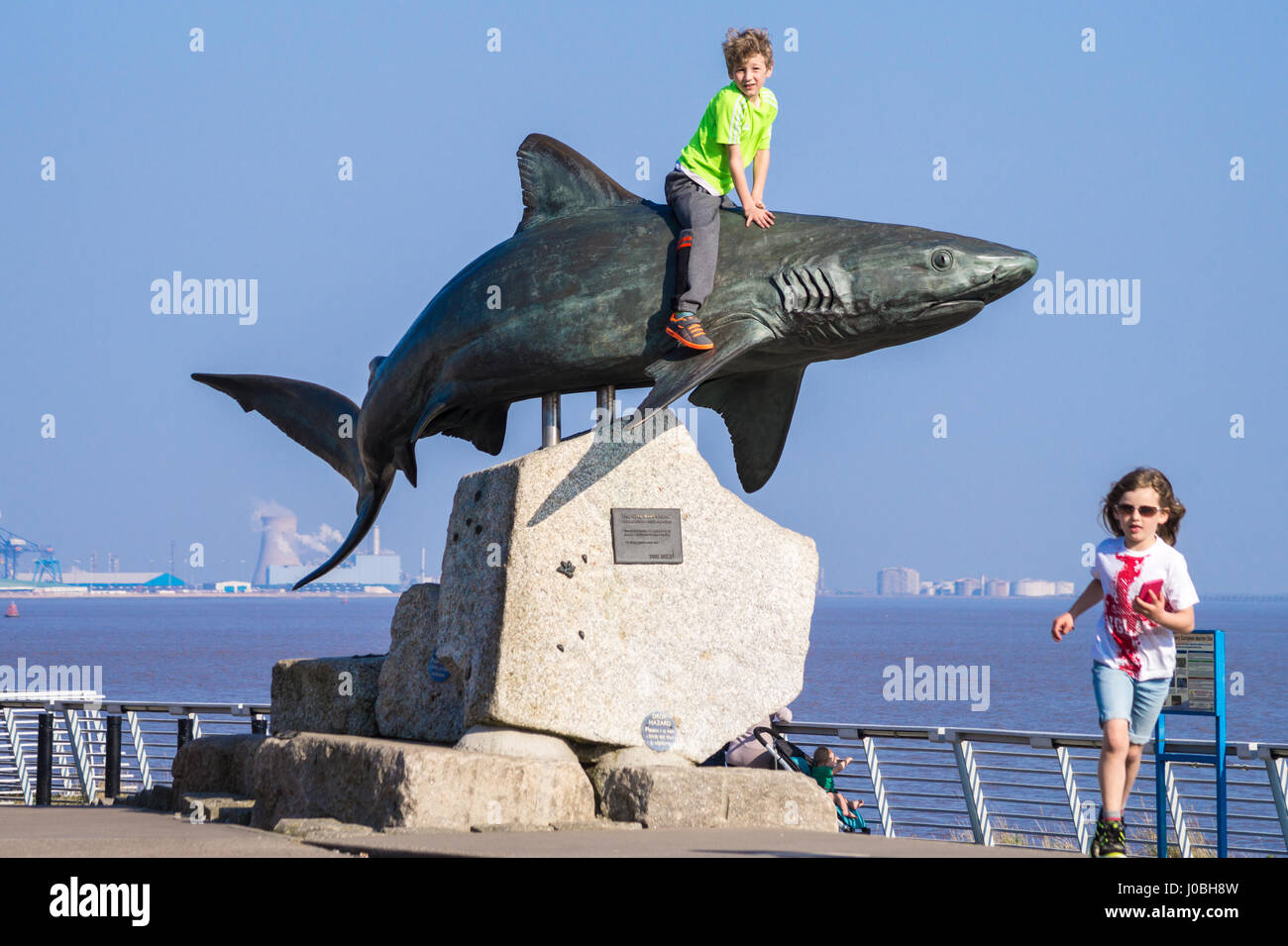 Small boy sitting on "Shark", bronze sculpture of grey reef shark by ...