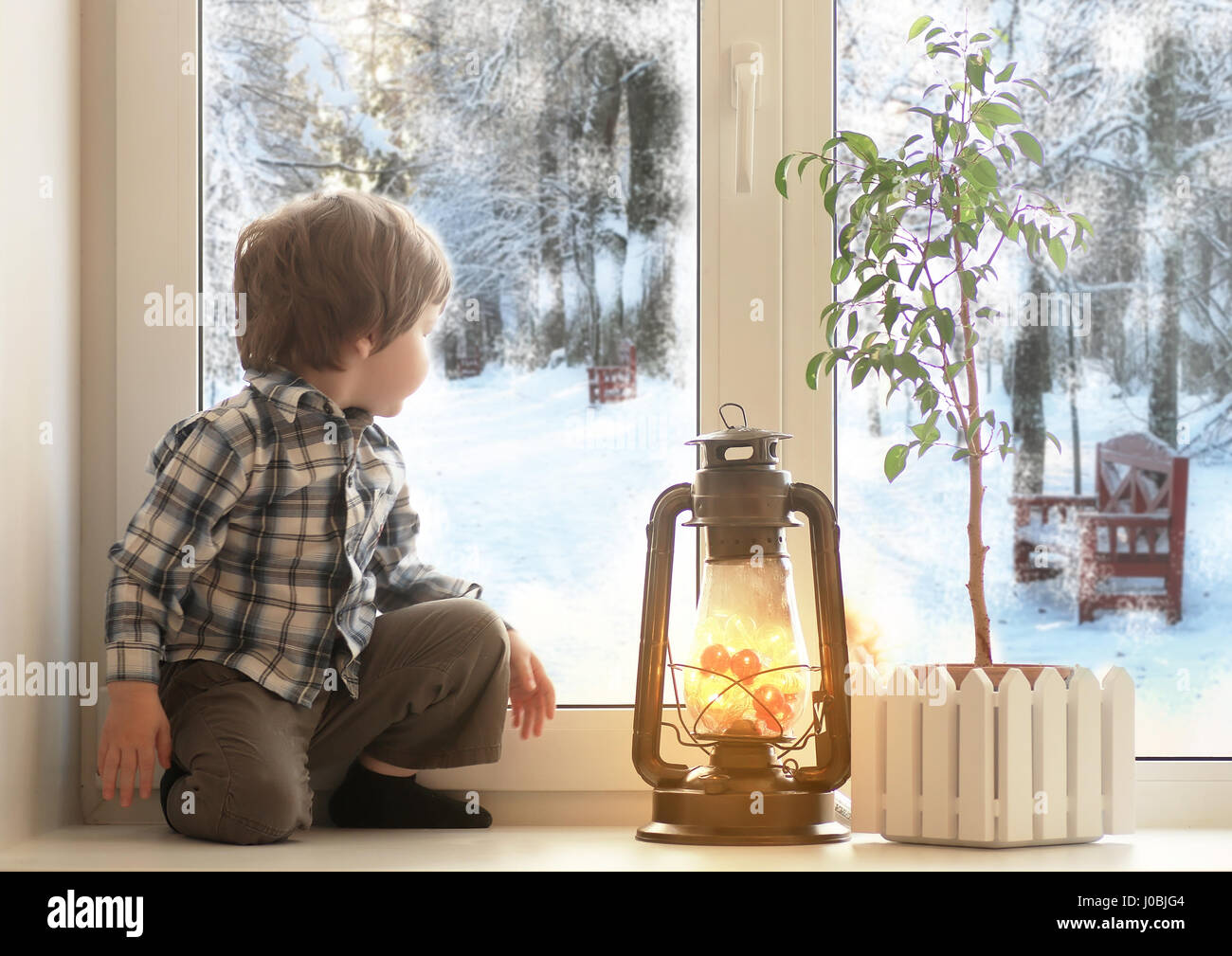 boy sitting on a white window sill and looks out the window Stock Photo ...