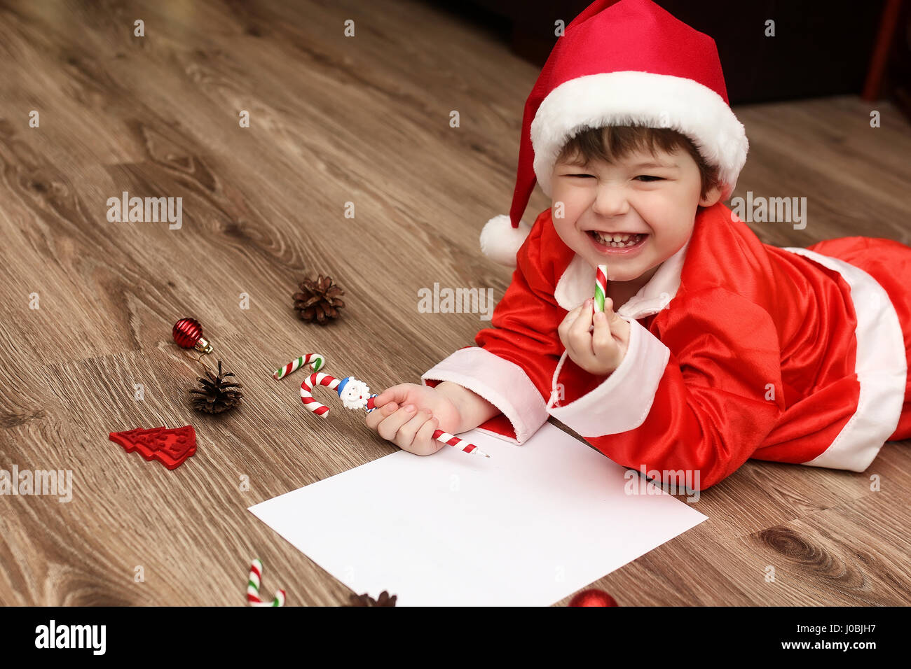 child in a suit of Santa Claus writing a letter with wishes for Stock ...