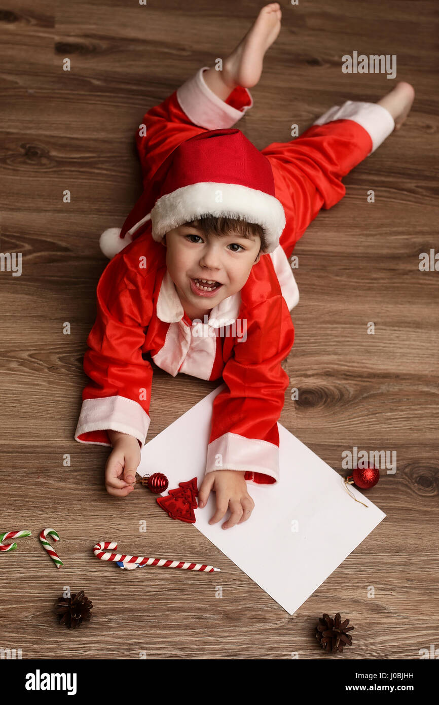 child in a suit of Santa Claus writing a letter with wishes for Stock ...