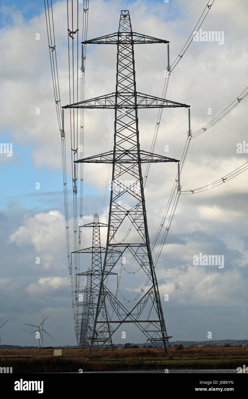 Row of electrical pylons with a wind turbine in the back ground Stock ...