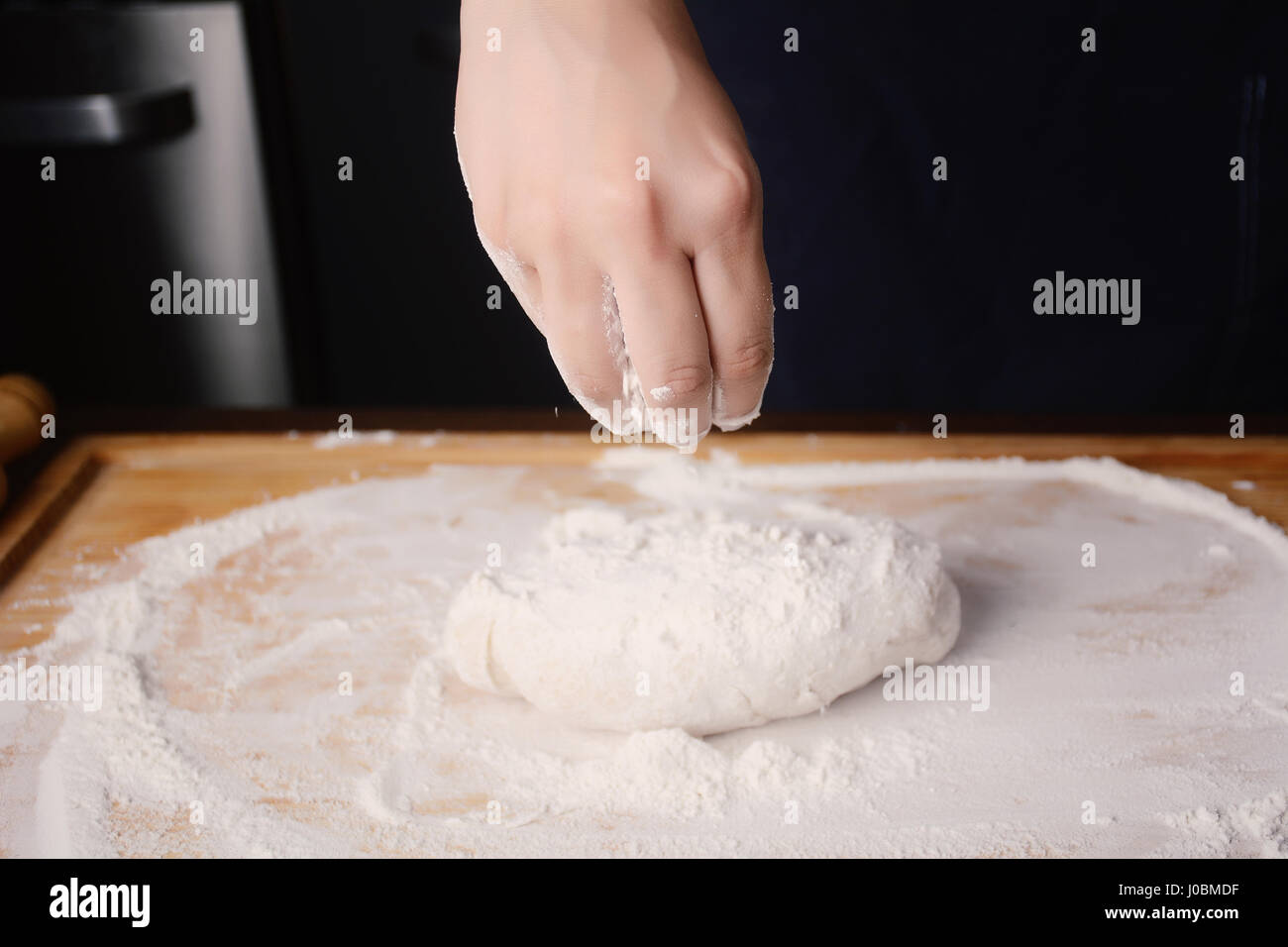 Close up of a woman hand adding flour to dough. Cooking concept Stock ...