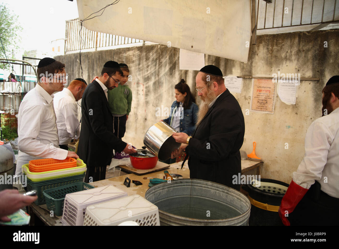 An Orthodox Jewish man examines a pot before taking it to immerse for ...