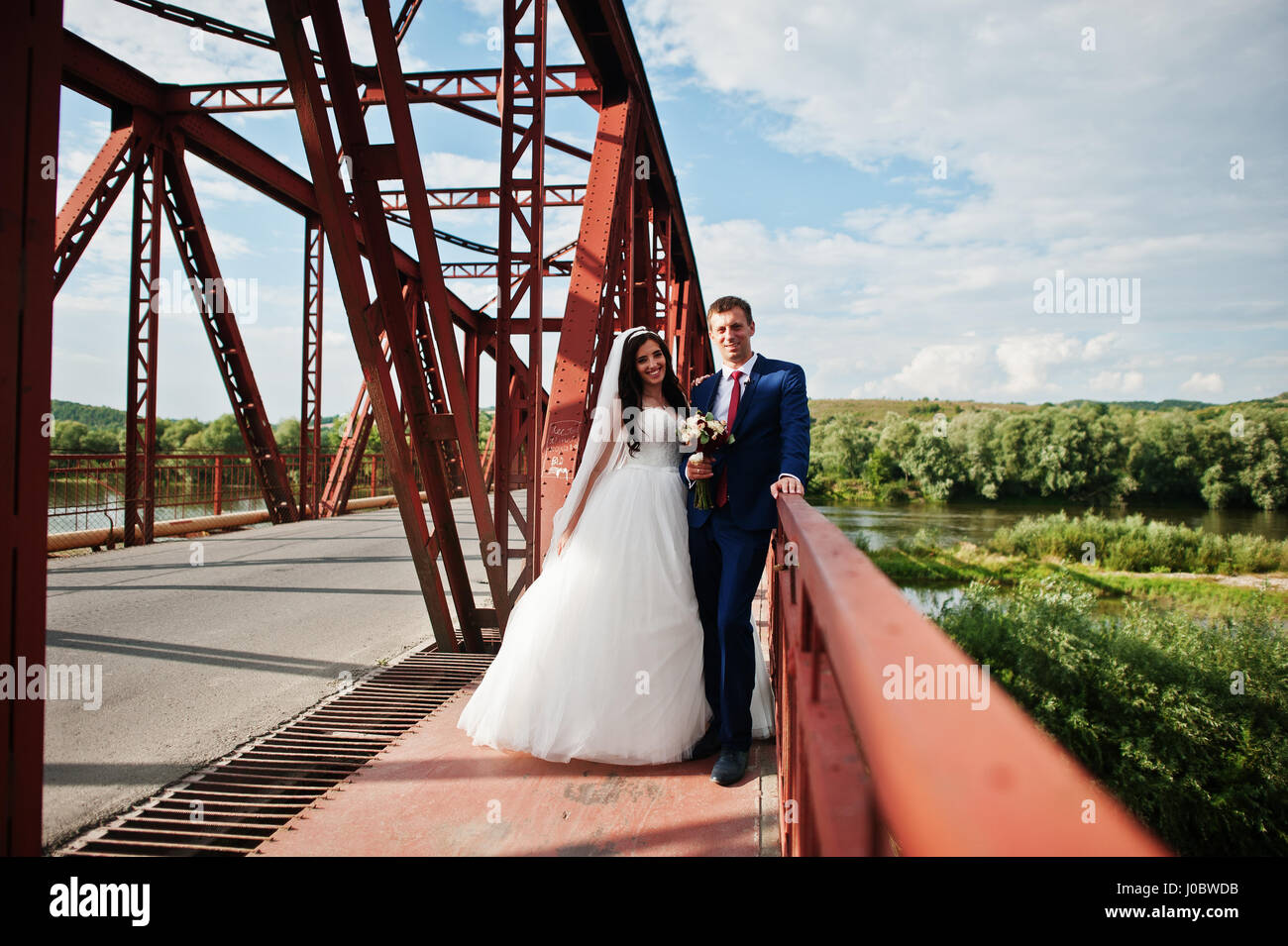Wedding couple in love stay at red railway bridge Stock Photo - Alamy