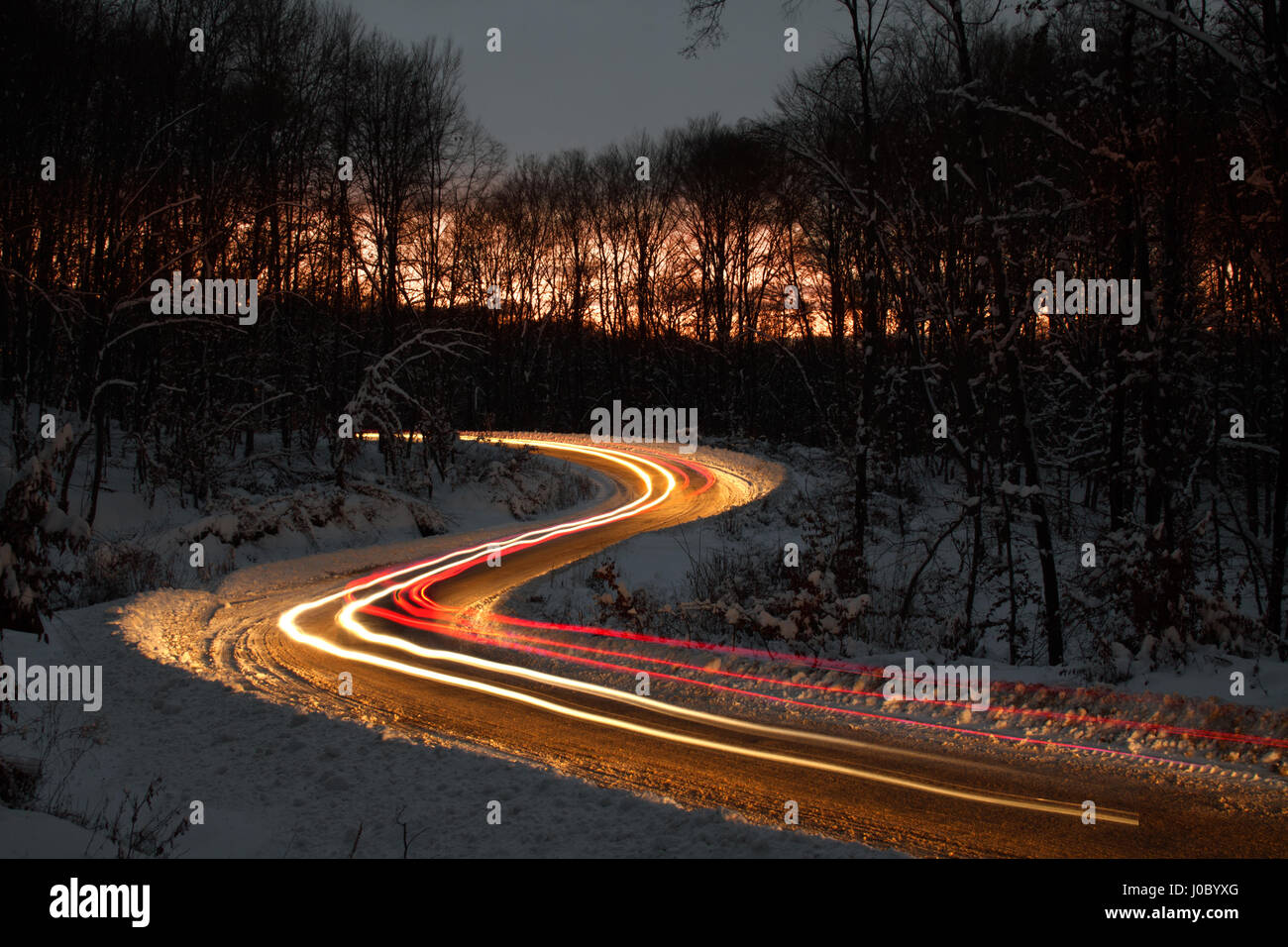 S curve on a forest road at night in the winter, just after sunset. The ...