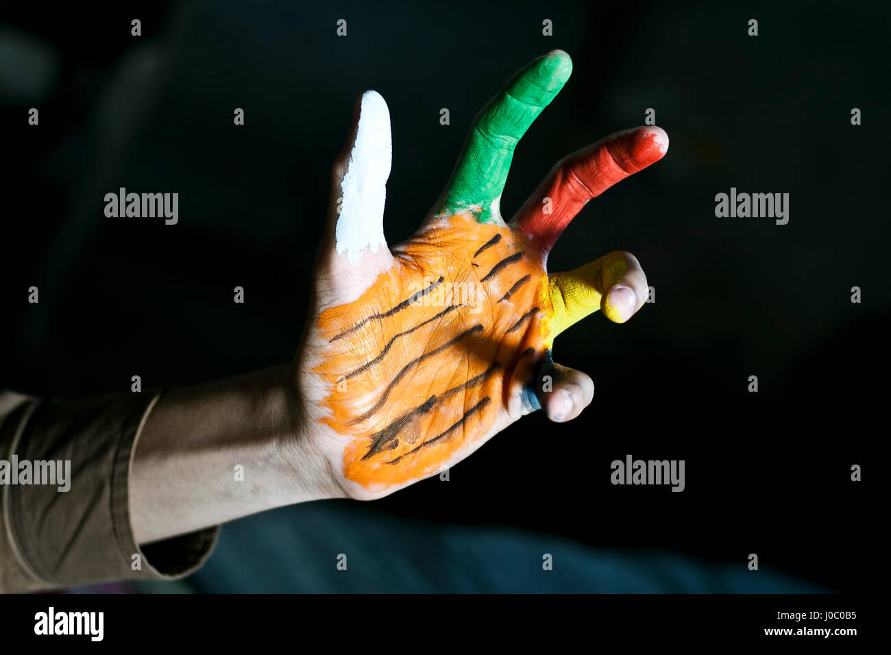 Tiger colored aggressive human painted hand with black strokes on it ...