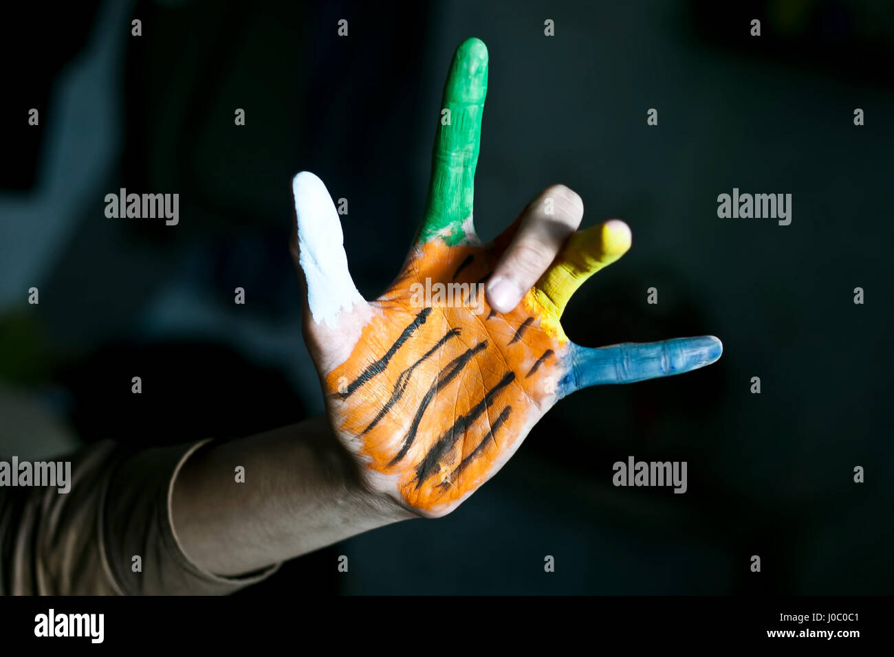 Tiger colored aggressive human painted hand with black strokes on it ...
