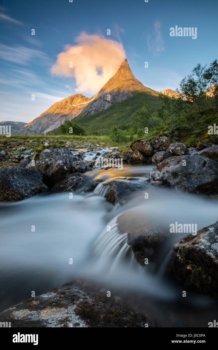 Waterfall frames the Stetinden mountain peak illuminated by midnight ...