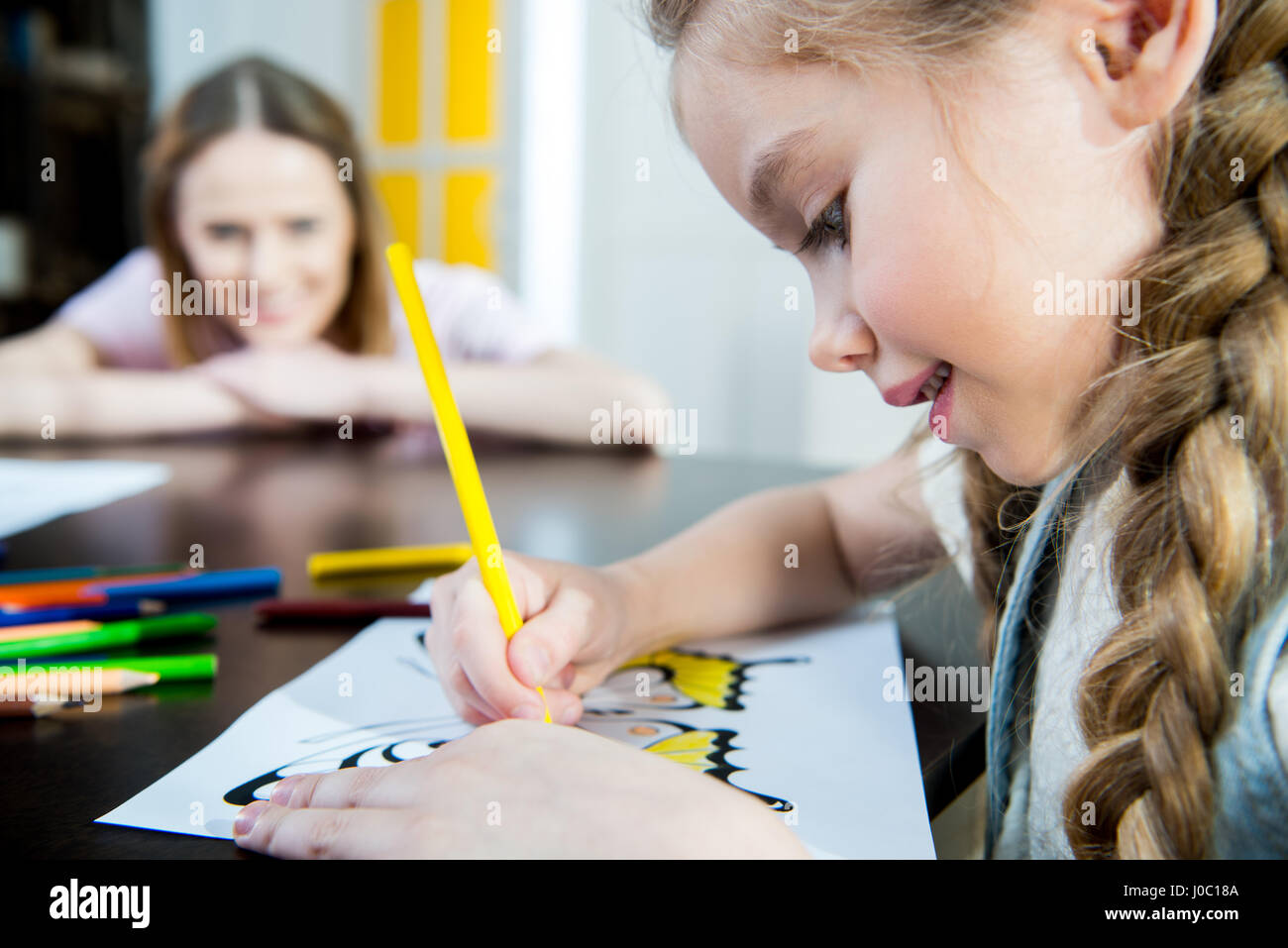 Happy adorable girl drawing with mother behind at home Stock Photo - Alamy