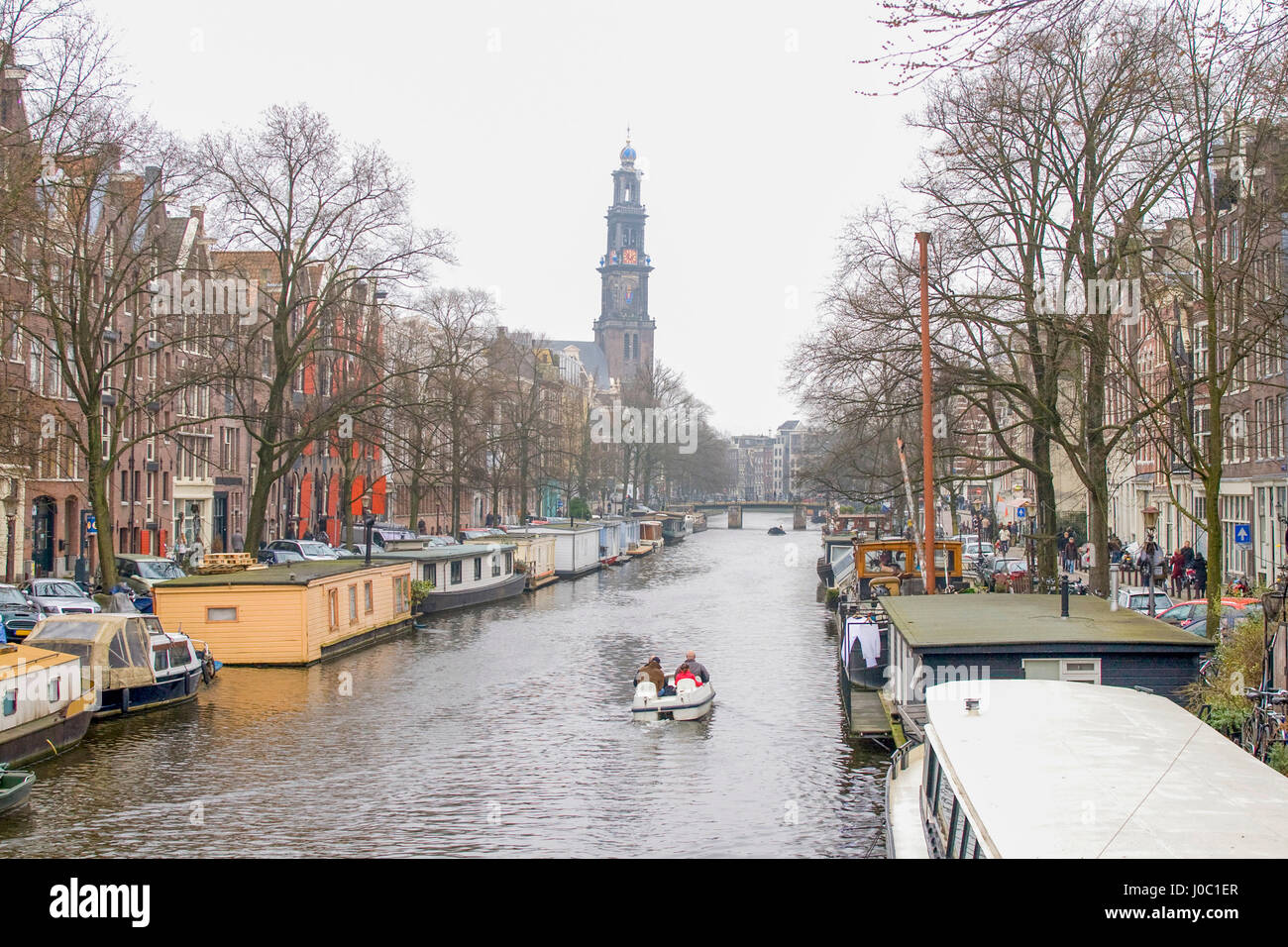 small motorboat on famous canal in Amsterdam with Westertoren in ...