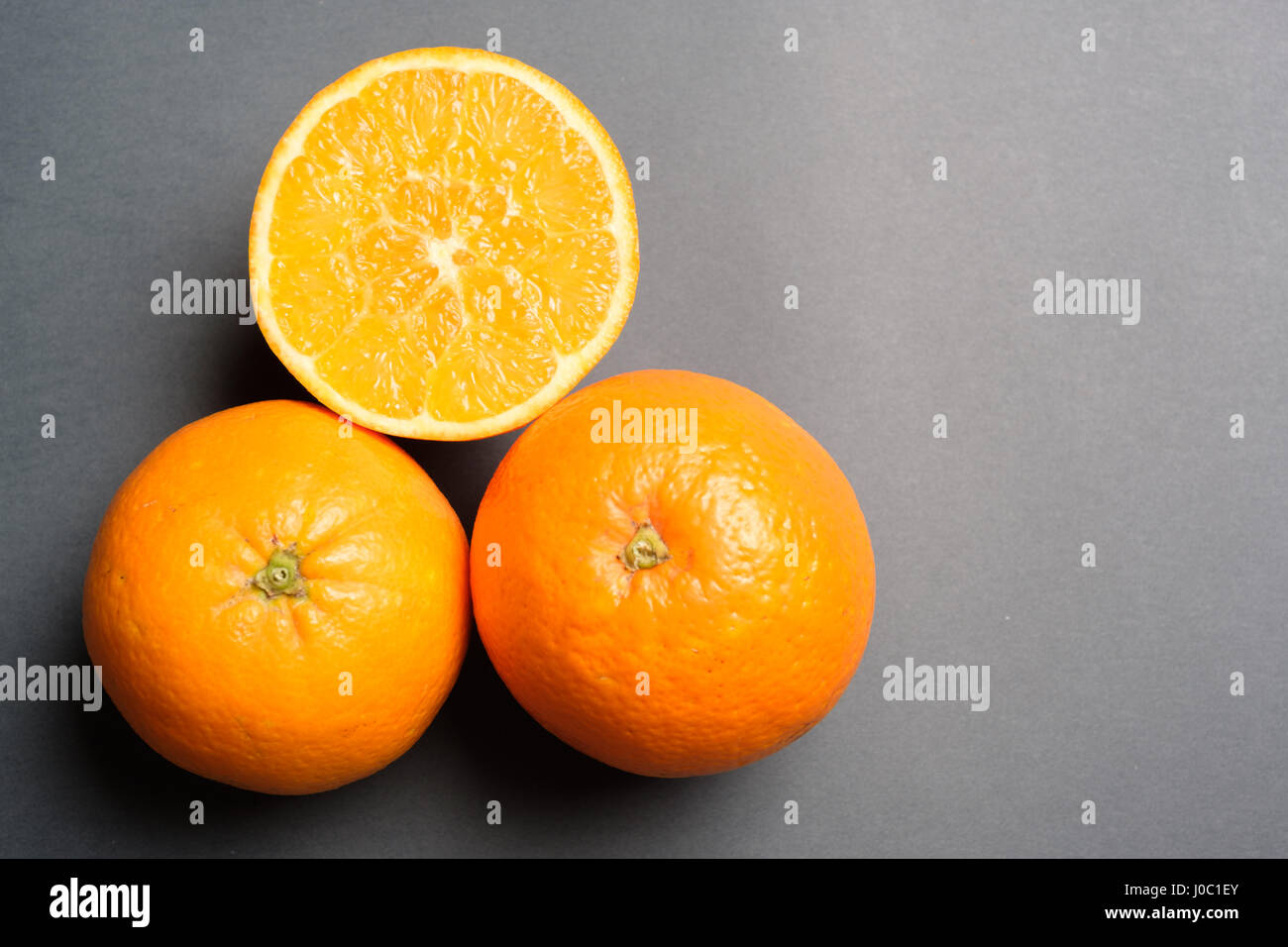 Three oranges on grey background Stock Photo - Alamy