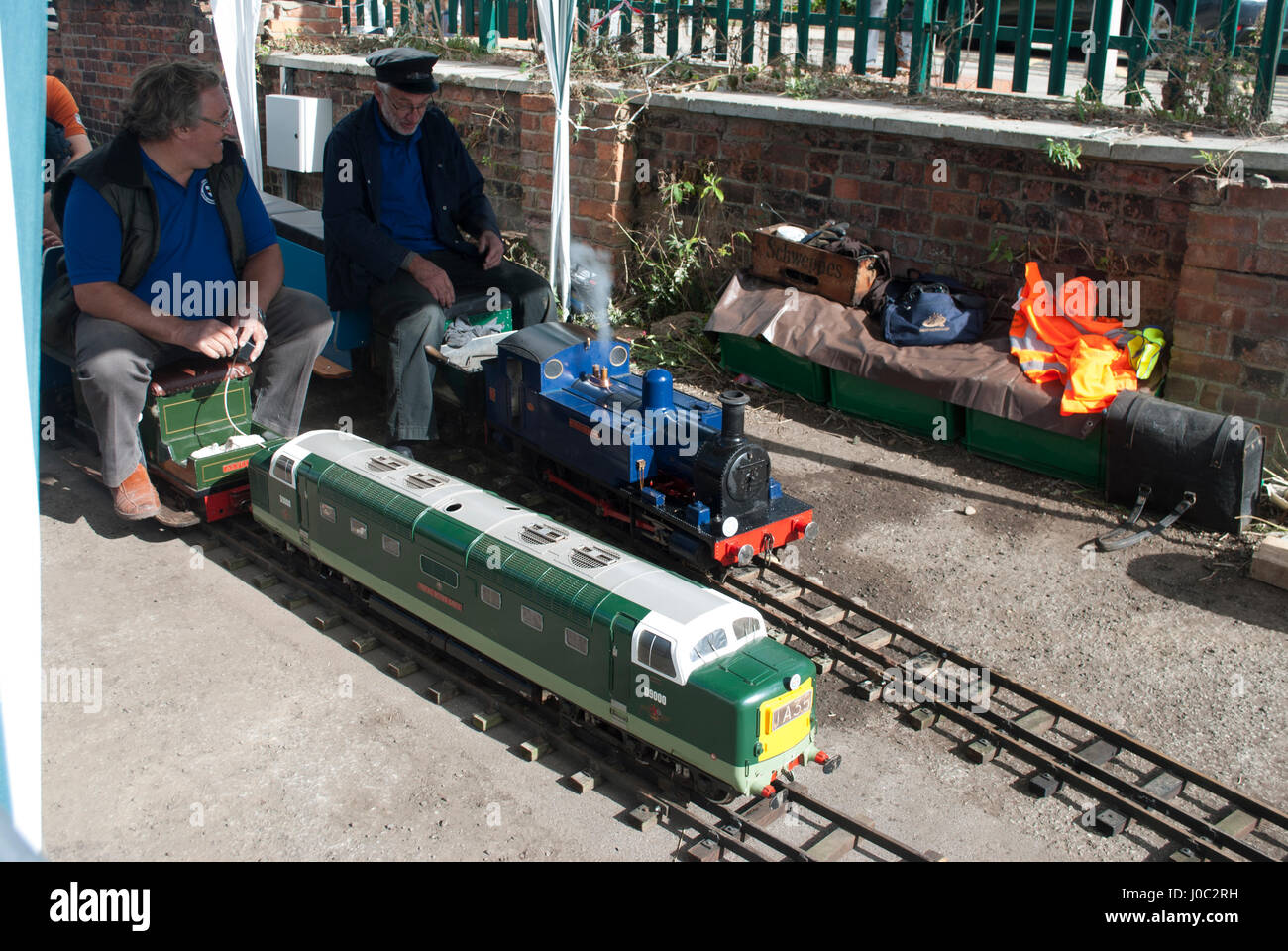 Men sitting on model trains Stock Photo - Alamy