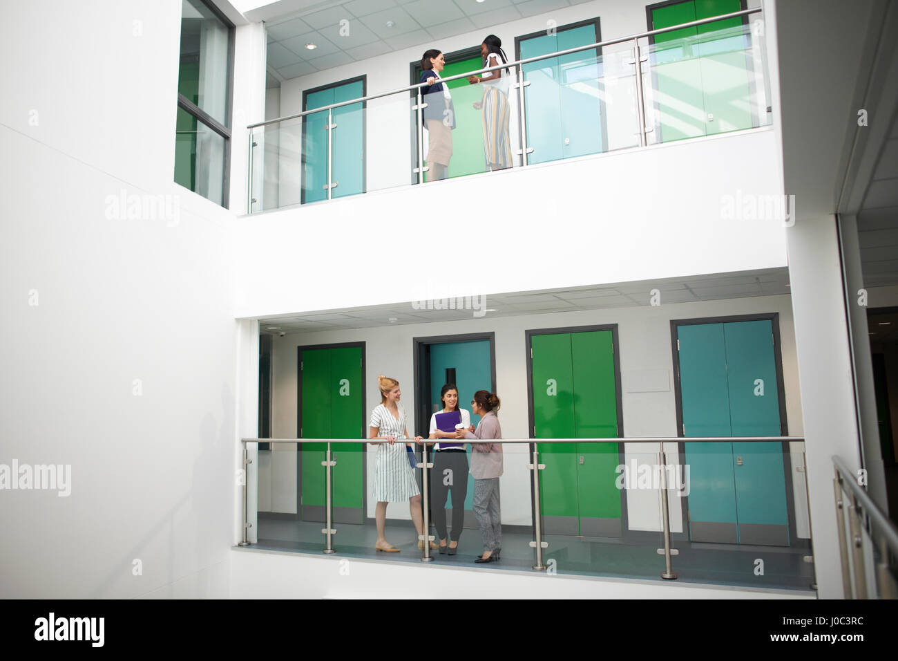 Colleagues on balcony in office building Stock Photo - Alamy
