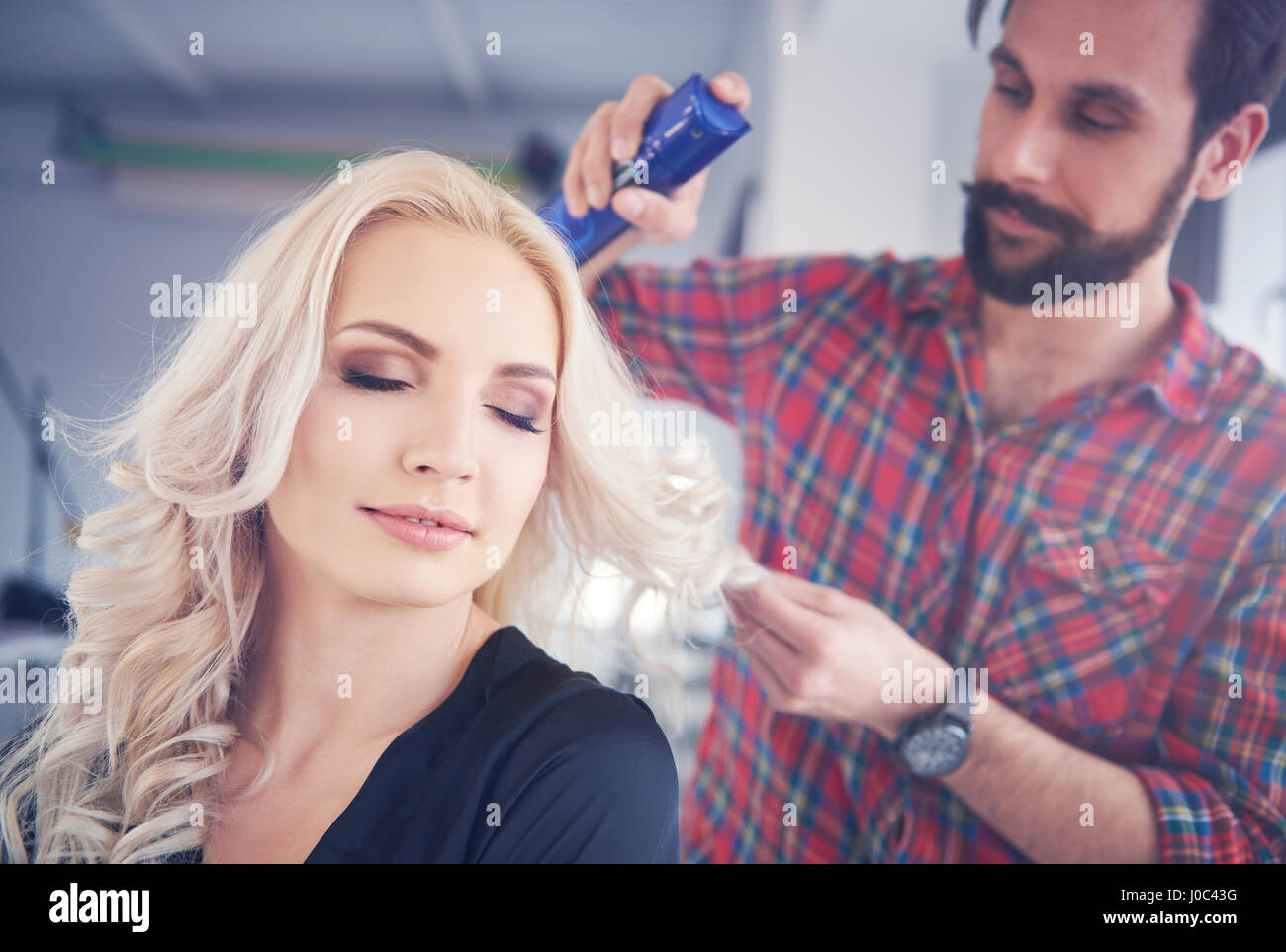 Male hairdresser putting hairspray on model for photo shoot Stock Photo ...
