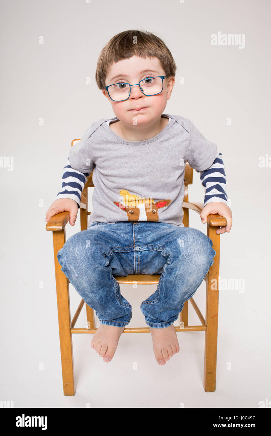 Portrait of young boy sitting in wooden chair Stock Photo - Alamy