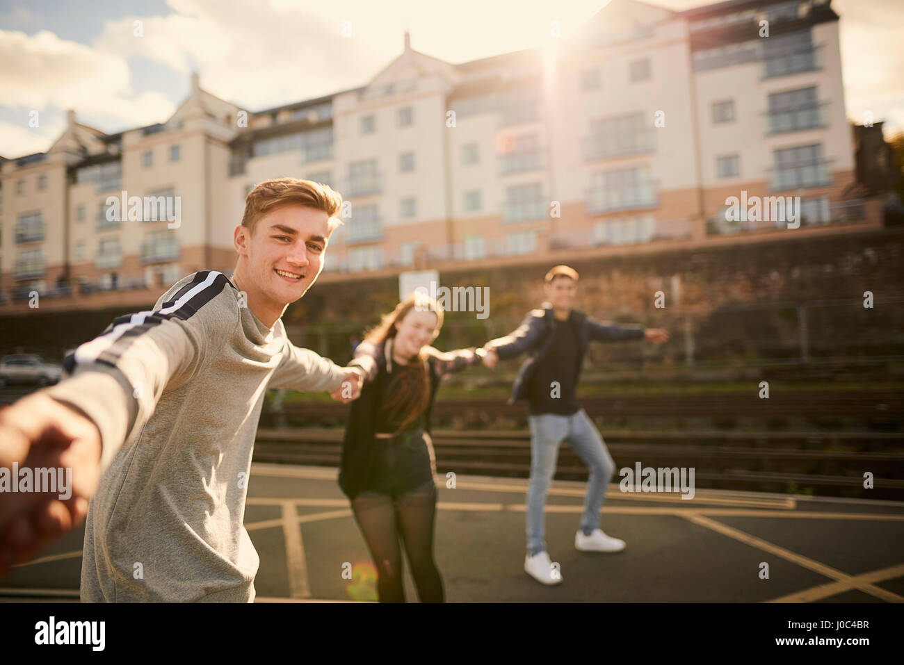 Three friends fooling around outdoors, holding hands, Bristol, UK Stock ...