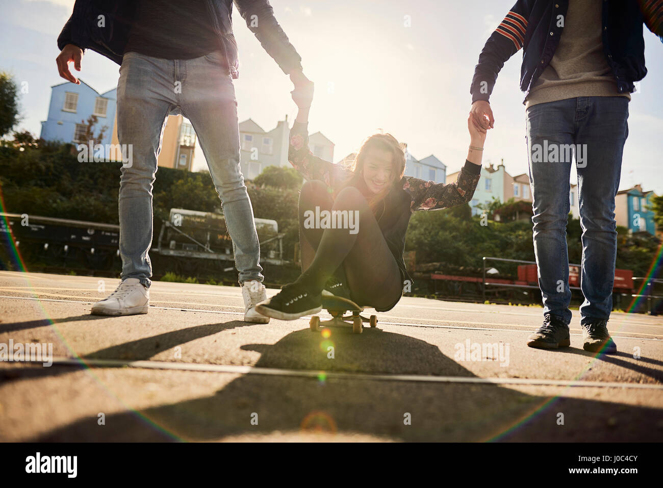 Three friends fooling around outdoors, young men pulling young woman ...