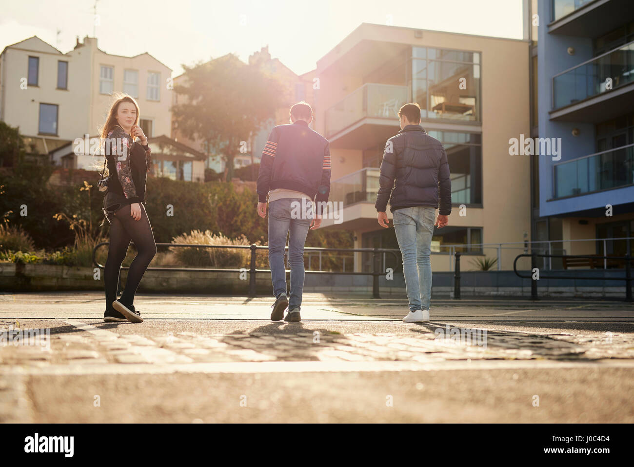 Three friends walking outdoors, young woman looking over shoulder ...