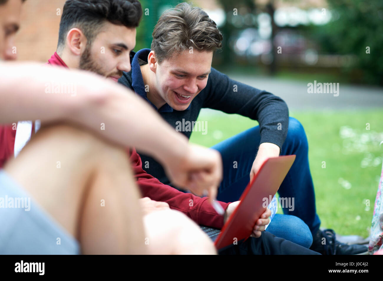 Three male friends, sitting outdoors, looking at digital tablet Stock ... Three male friends, sitting outdoors, looking at digital tablet Stock ...
