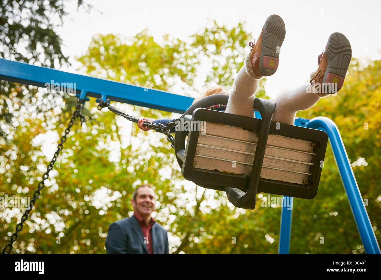 Father pushing daughter on playground swing Stock Photo - Alamy