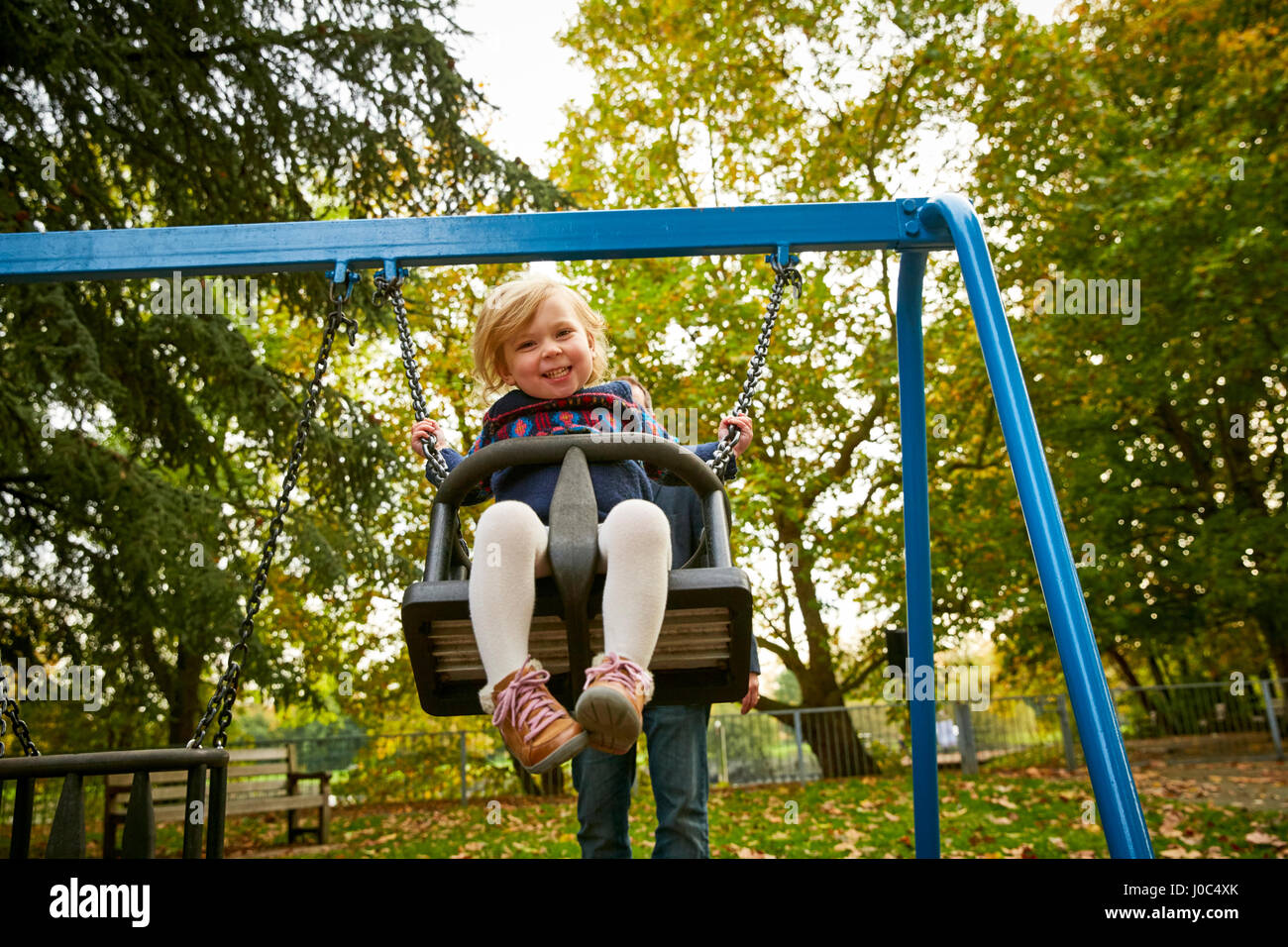 Father pushing daughter on playground swing Stock Photo - Alamy