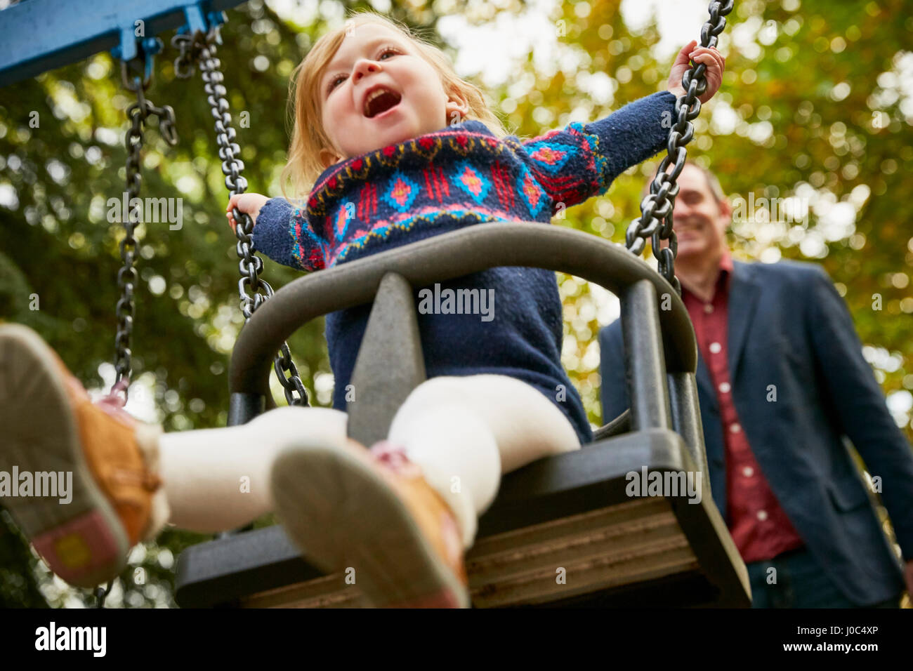 Father pushing daughter on playground swing Stock Photo - Alamy