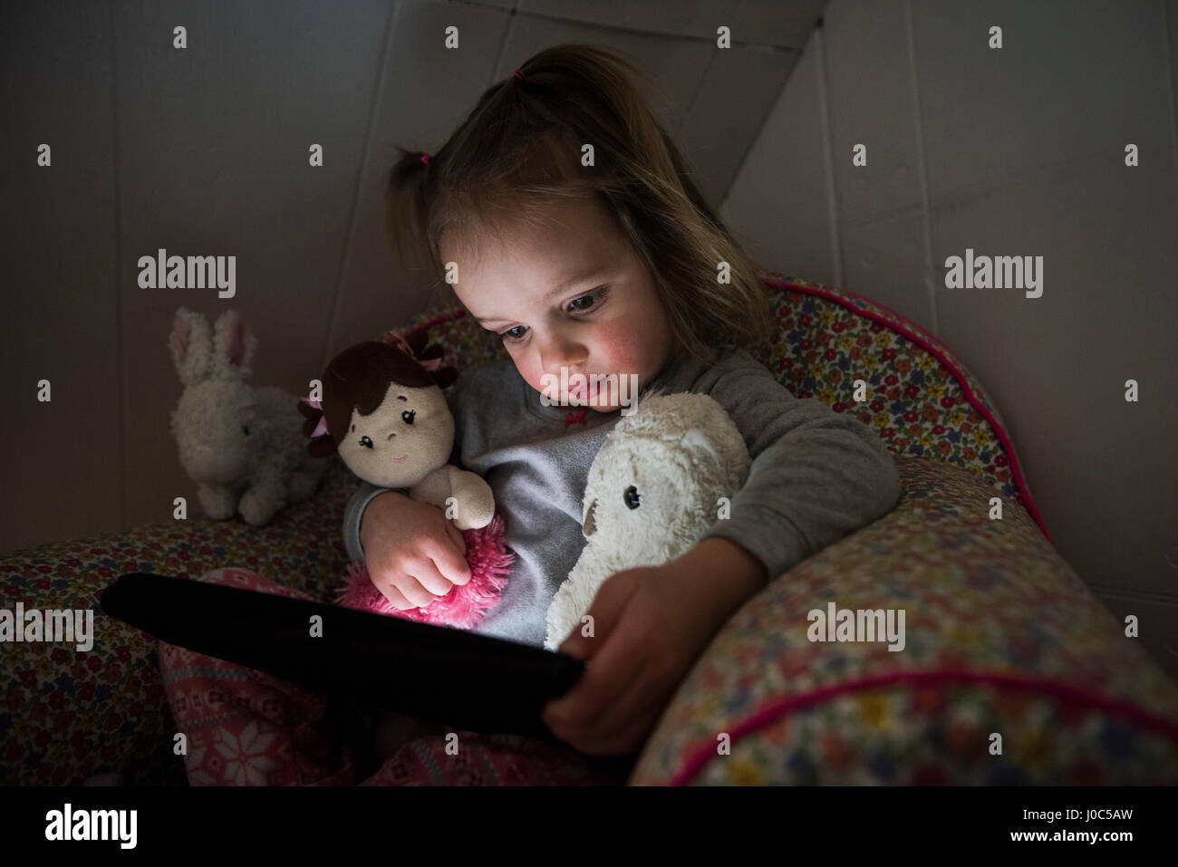Female toddler sitting up in bed staring at digital tablet Stock Photo ...
