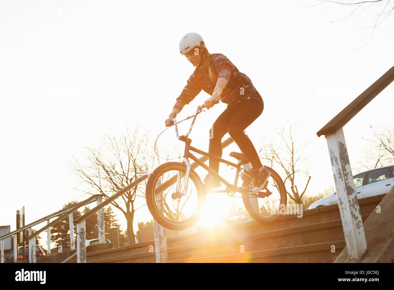 Female BMX rider riding down sunlit stairway Stock Photo - Alamy
