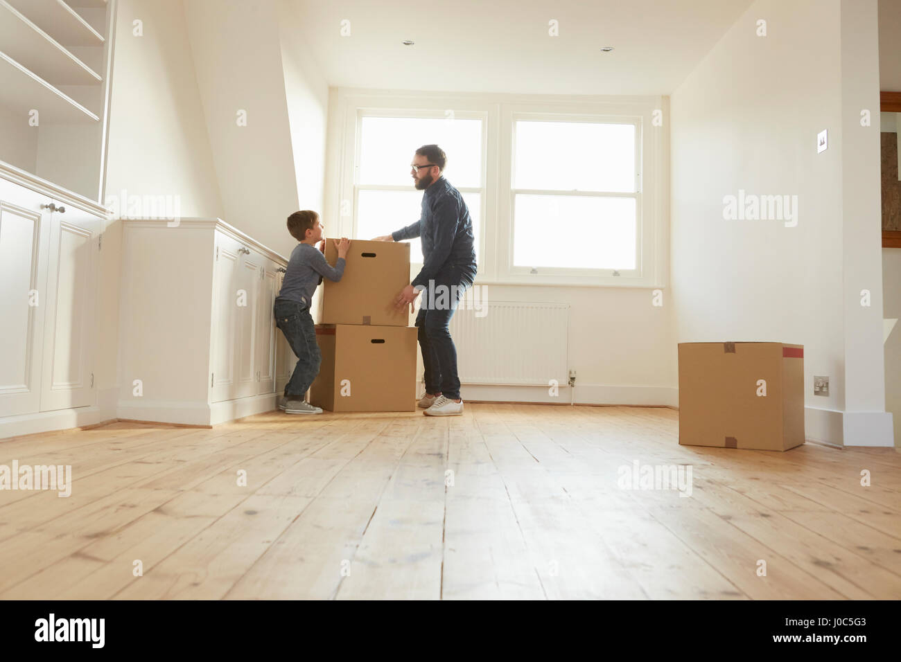Mid adult man and son stacking cardboard box in new home Stock Photo ...