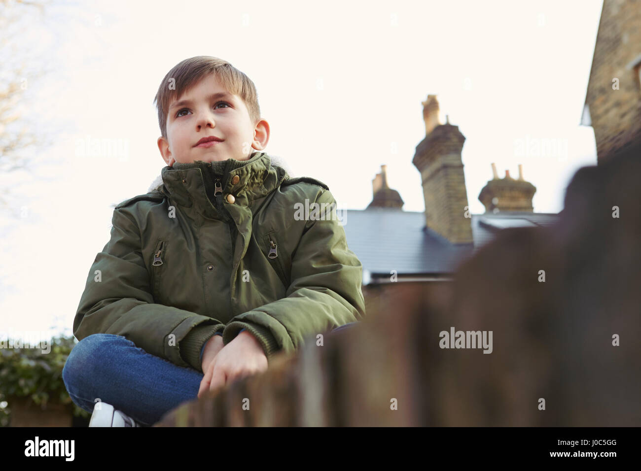 Portrait of boy sitting looking out from wall Stock Photo - Alamy